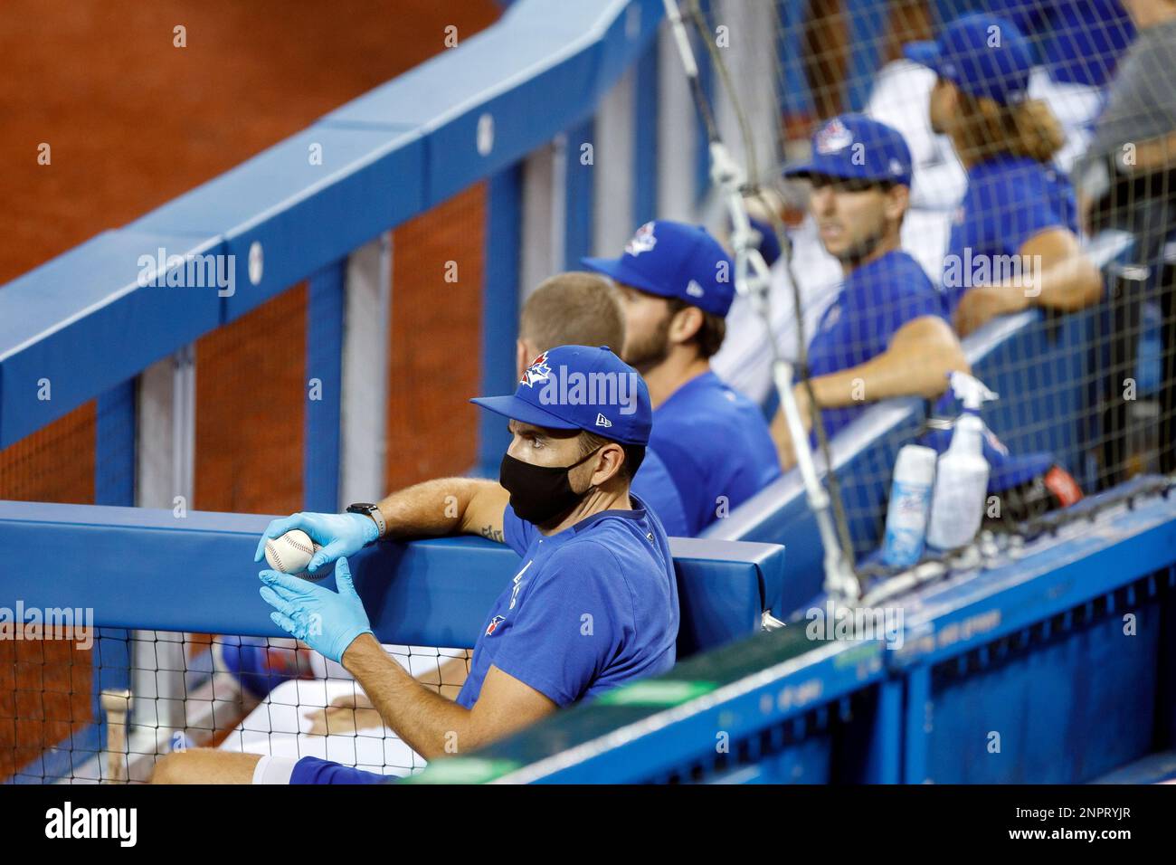 A Toronto Blue Jays staff member wearing gloves and a mask looks on ...