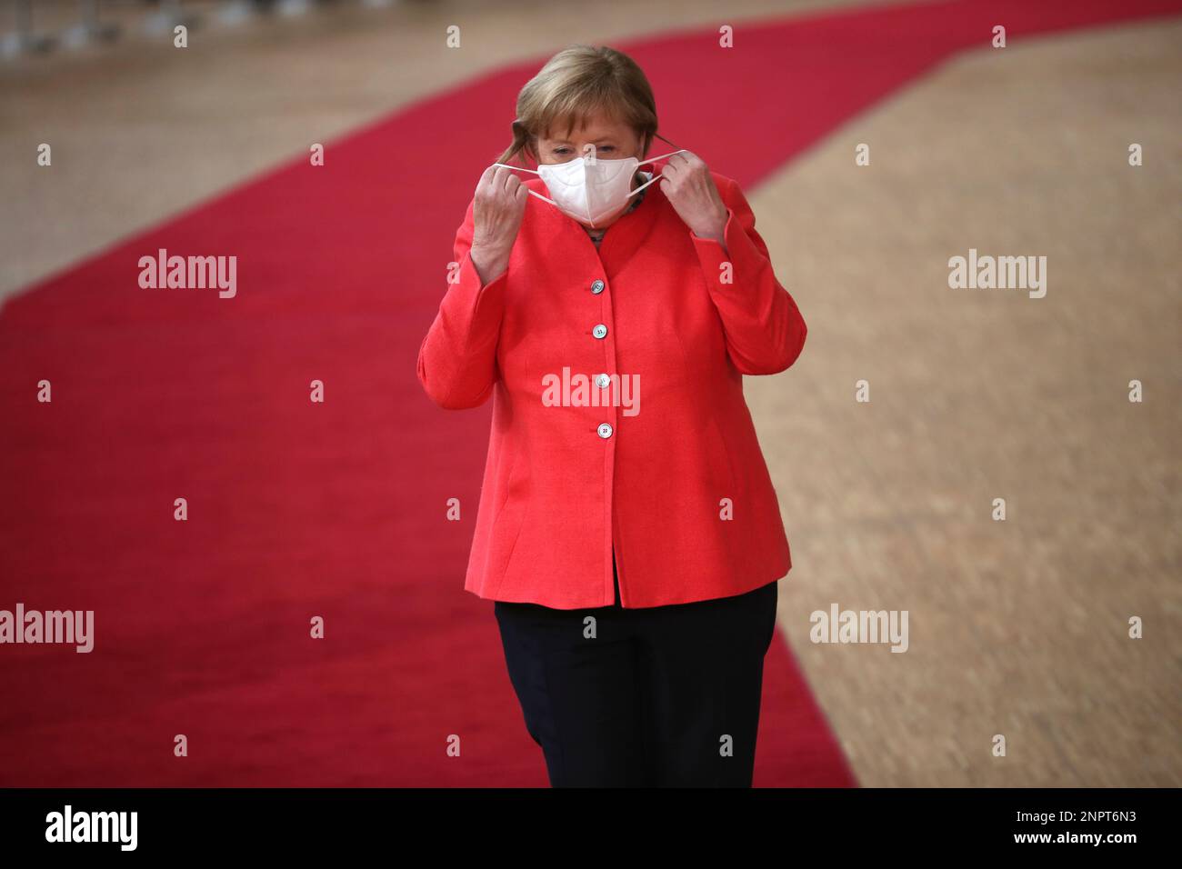 German Chancellor Angela Merkel prepares to remove her protective mask ...