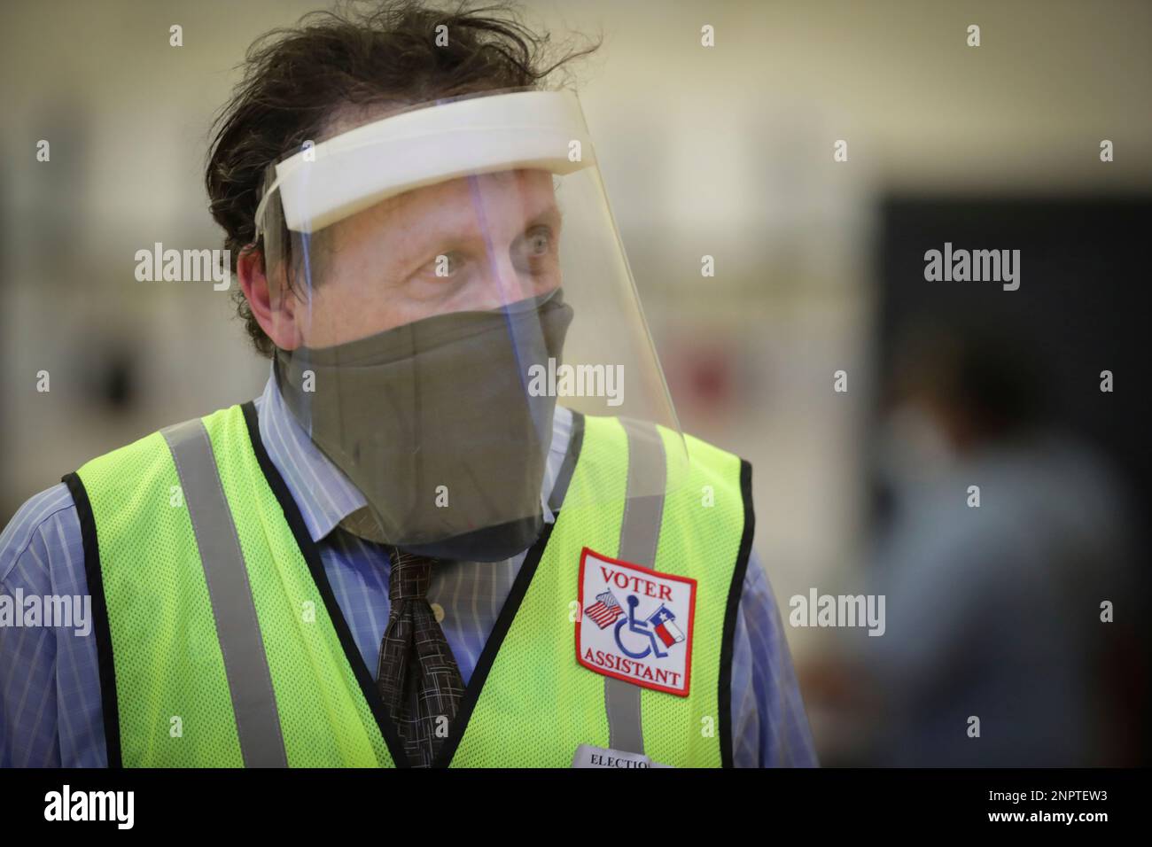 Voter essistant Marvin Hass, wearing a face mask and shield, aids ...