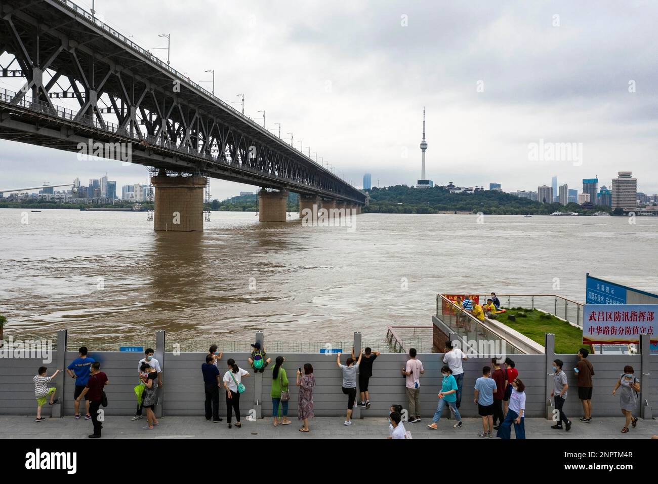 People look out from the temporary flood wall along the Yangtze River ...