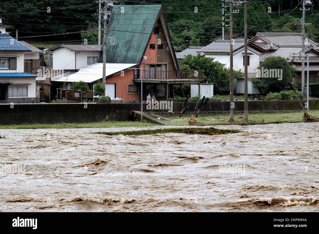 People look at swollen Hida river following heavy rain in Gero, Gifu ...