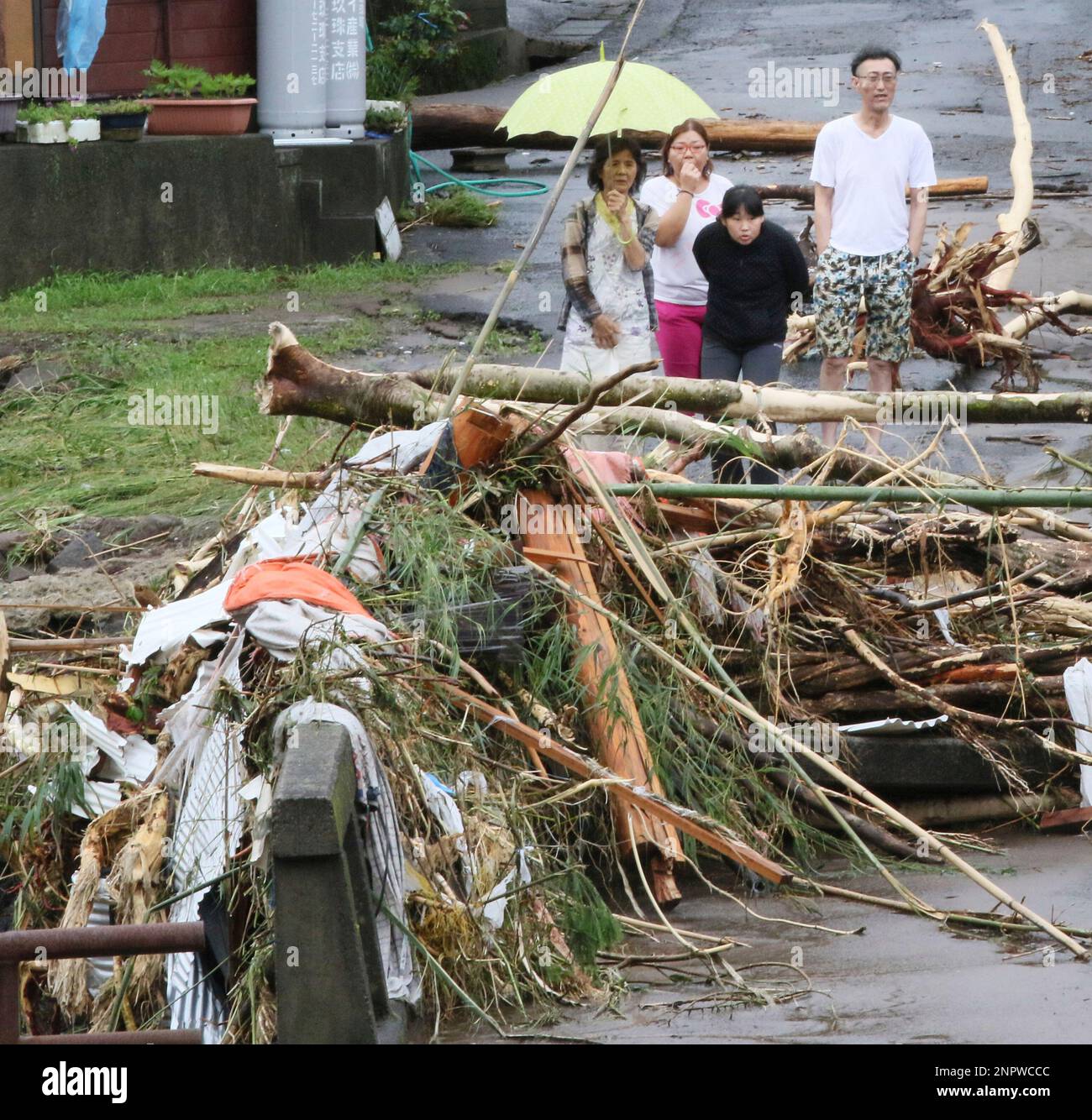 Local residents look stunned to see debris washed away by a flooding of ...