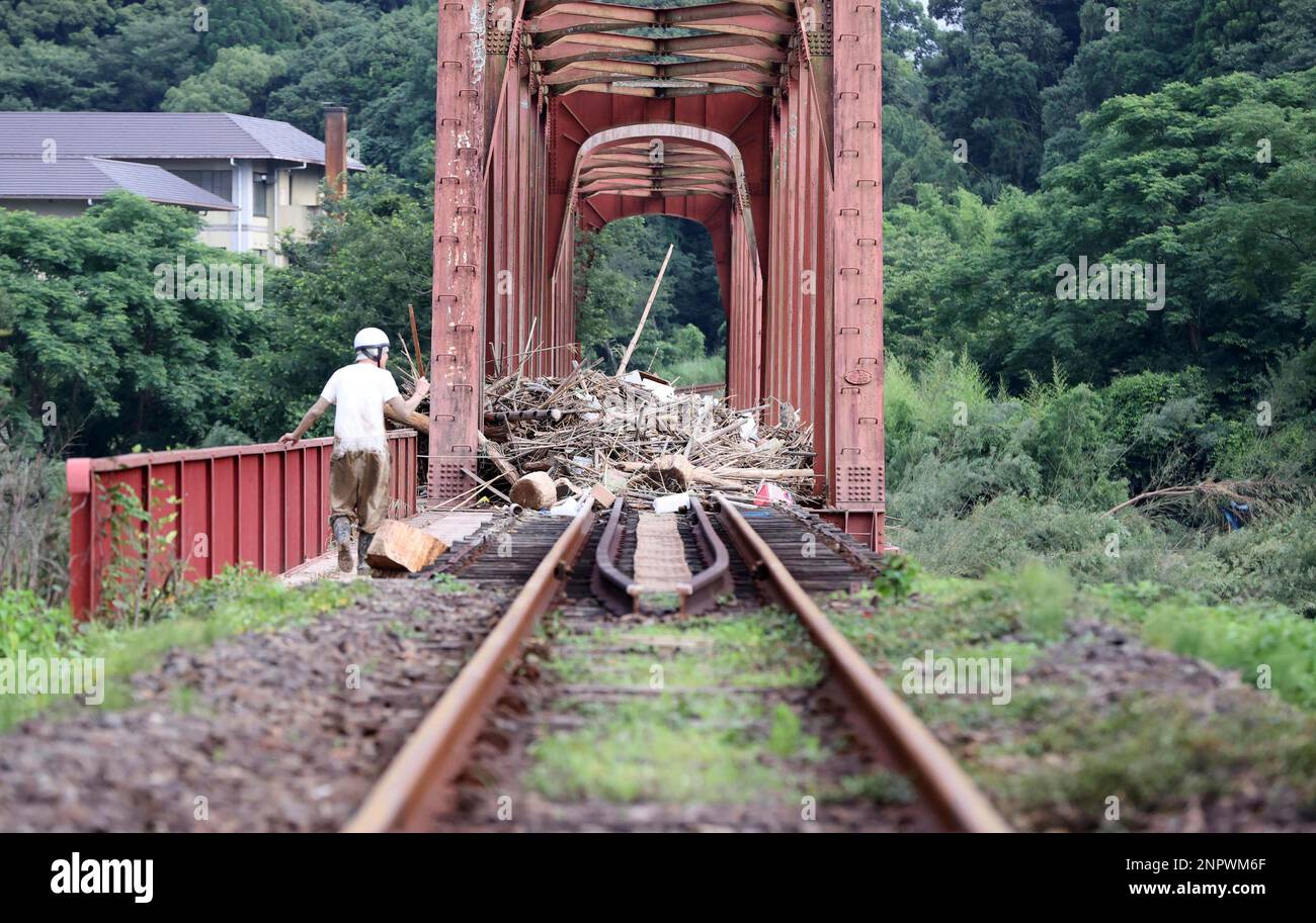 Huge tree branches and timbers get stuck on a railway bridge of JR Line ...