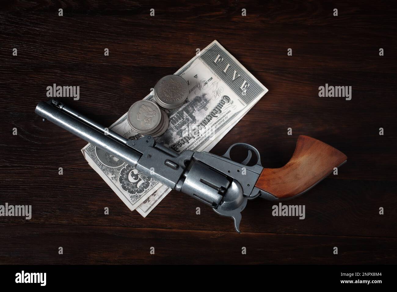 Old west revolver with bill and silver dollars on wooden table Stock ...