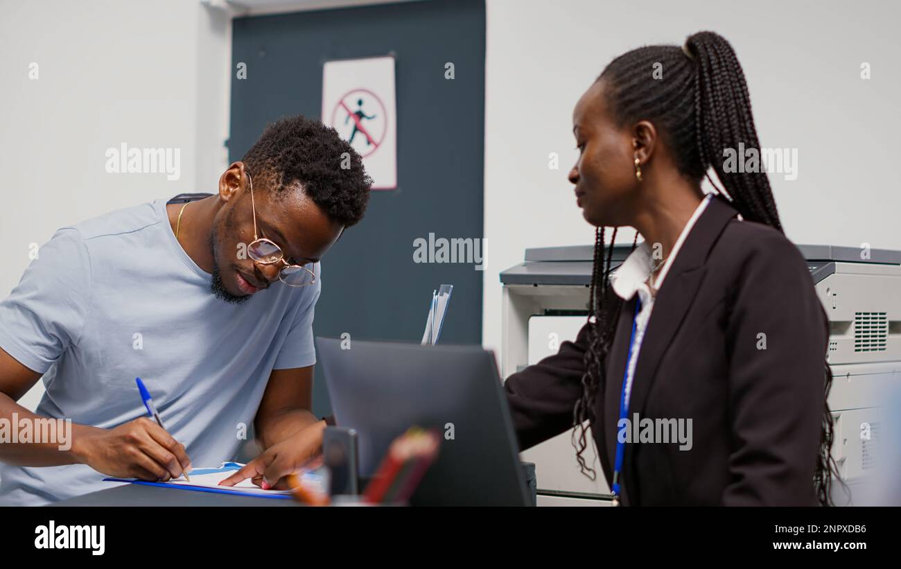 Young sick person filling in medical form papers at hospital reception ...