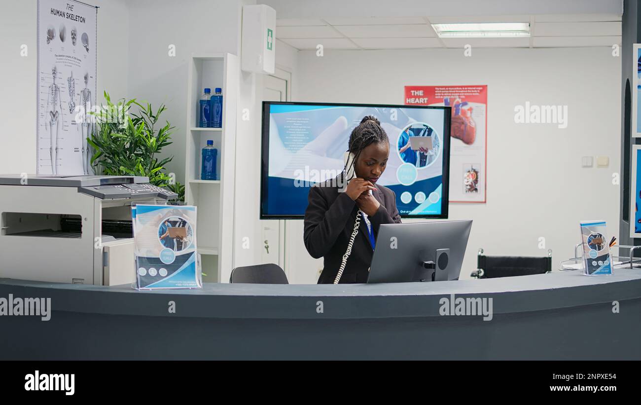 African american receptionist working at hospital reception counter ...