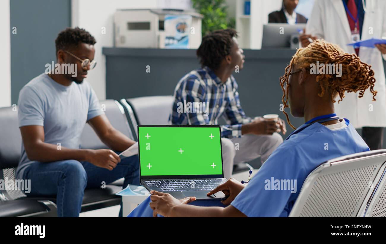 African american nurse looking at laptop with greenscreen, analyzing ...