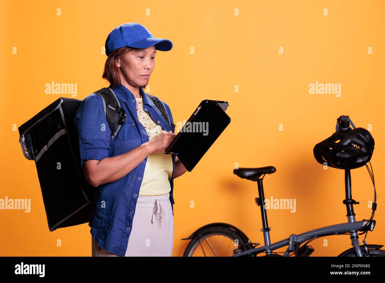 Concentrated elderly deliverywoman holding digital device checking ...