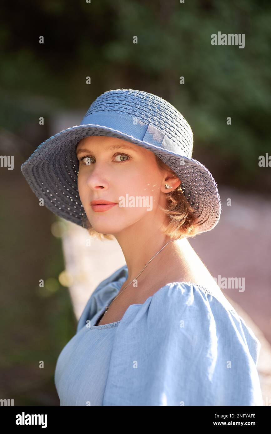 Close-up portrait of middle aged woman in blue straw hat with blue eyes ...