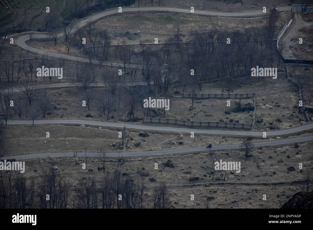 A motorcyclist rides along the road during a cloudy winter day in ...