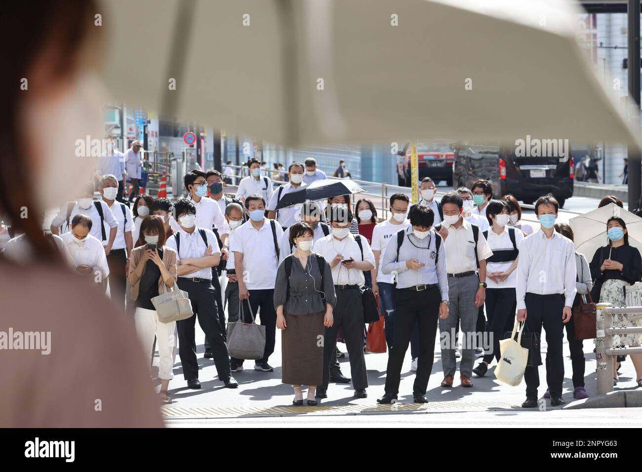 Commuters wearing masks walk near Shinjuku Station in Shinjuku Ward ...