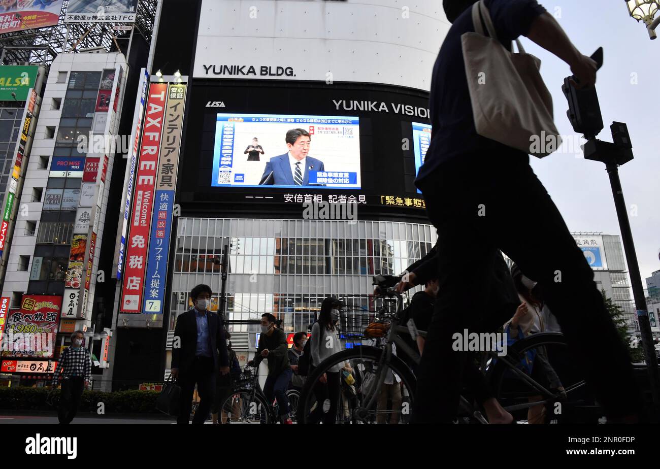 Passers-by watch the monitor display showing Prime Minister Shinzo Abe ...