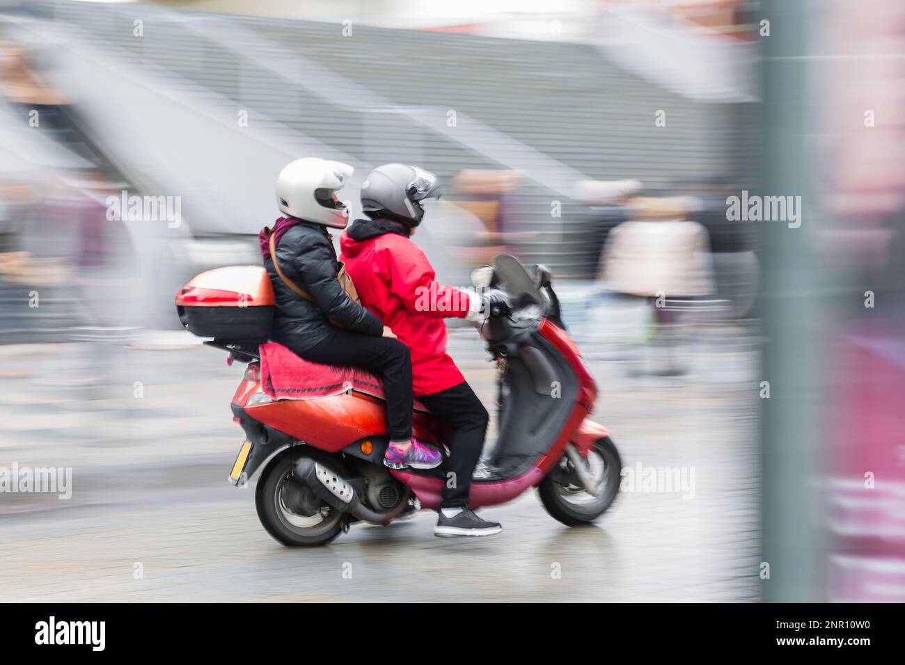 picture in intentional motion blur of a couple on a scooter driving in ...