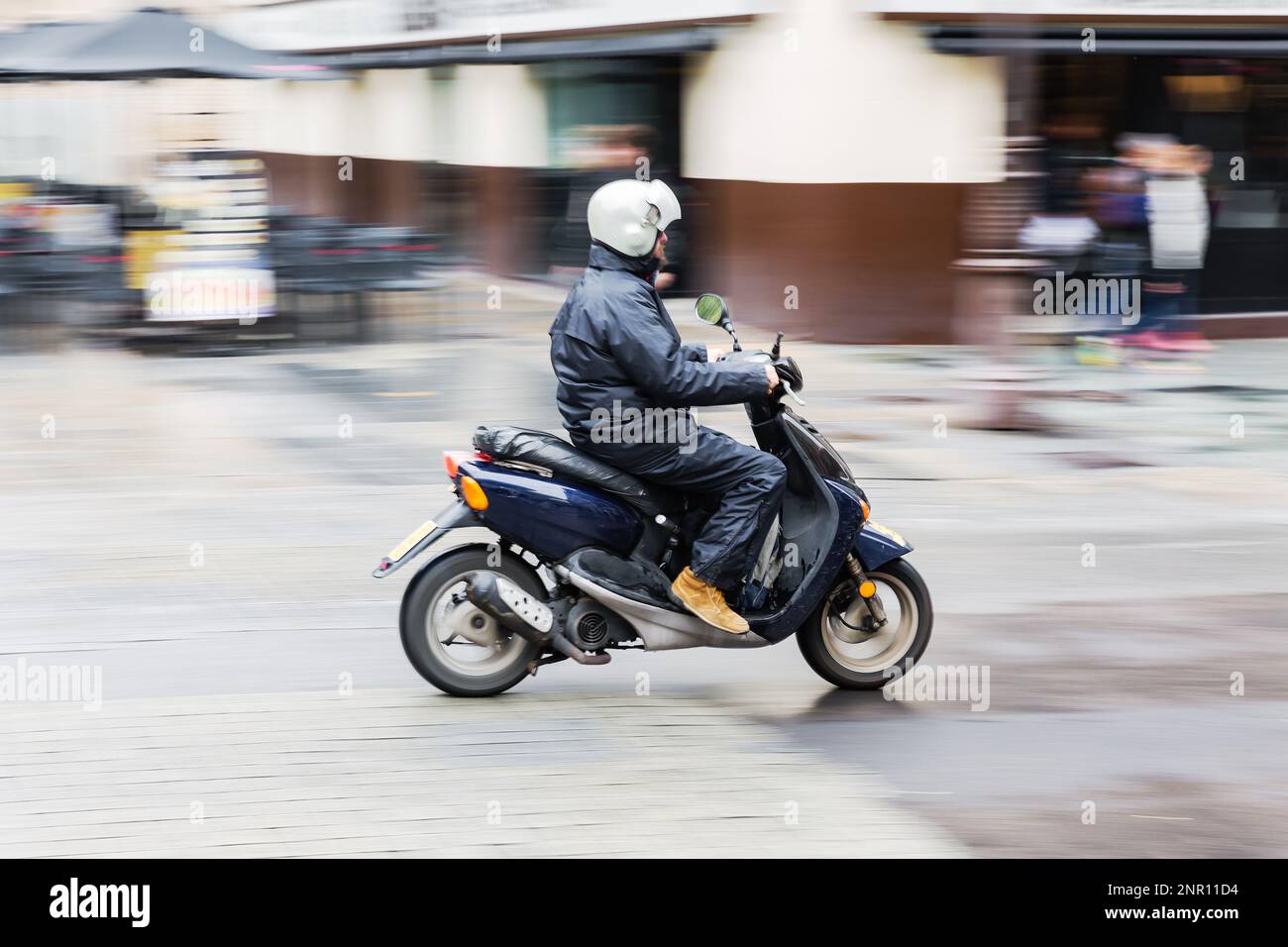 picture in intentional motion blur of a man with a scooter driving in ...