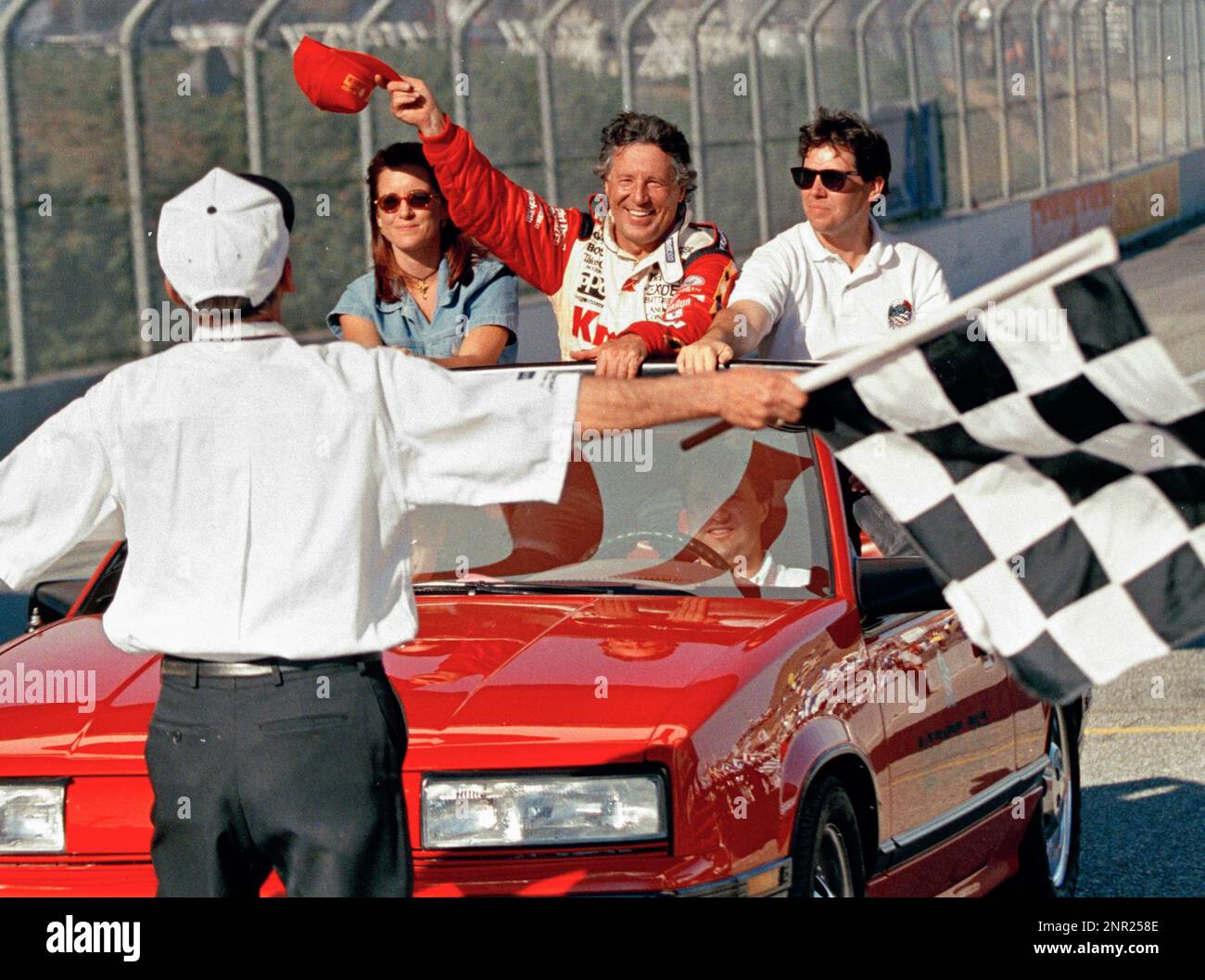 Mario Andretti (C) waves his hat as he approaches the ceremonial ...