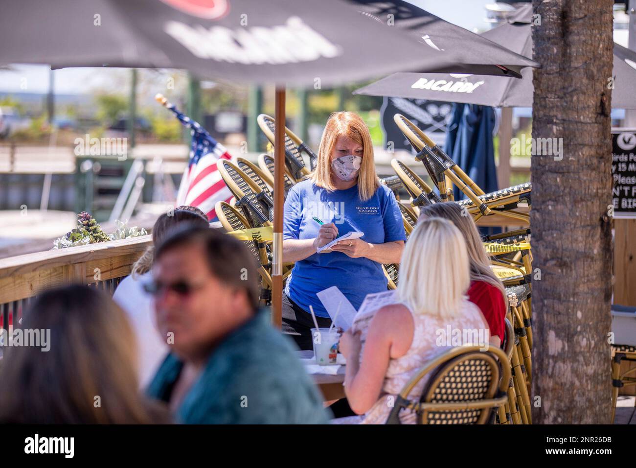 Jennifer Inman, wearing a mask, serves a table of diners at Dead Dog ...