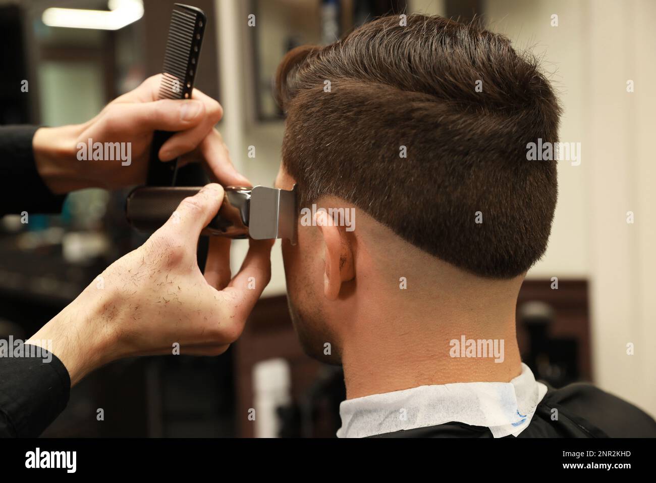 Professional hairdresser making stylish haircut in salon, back view ...