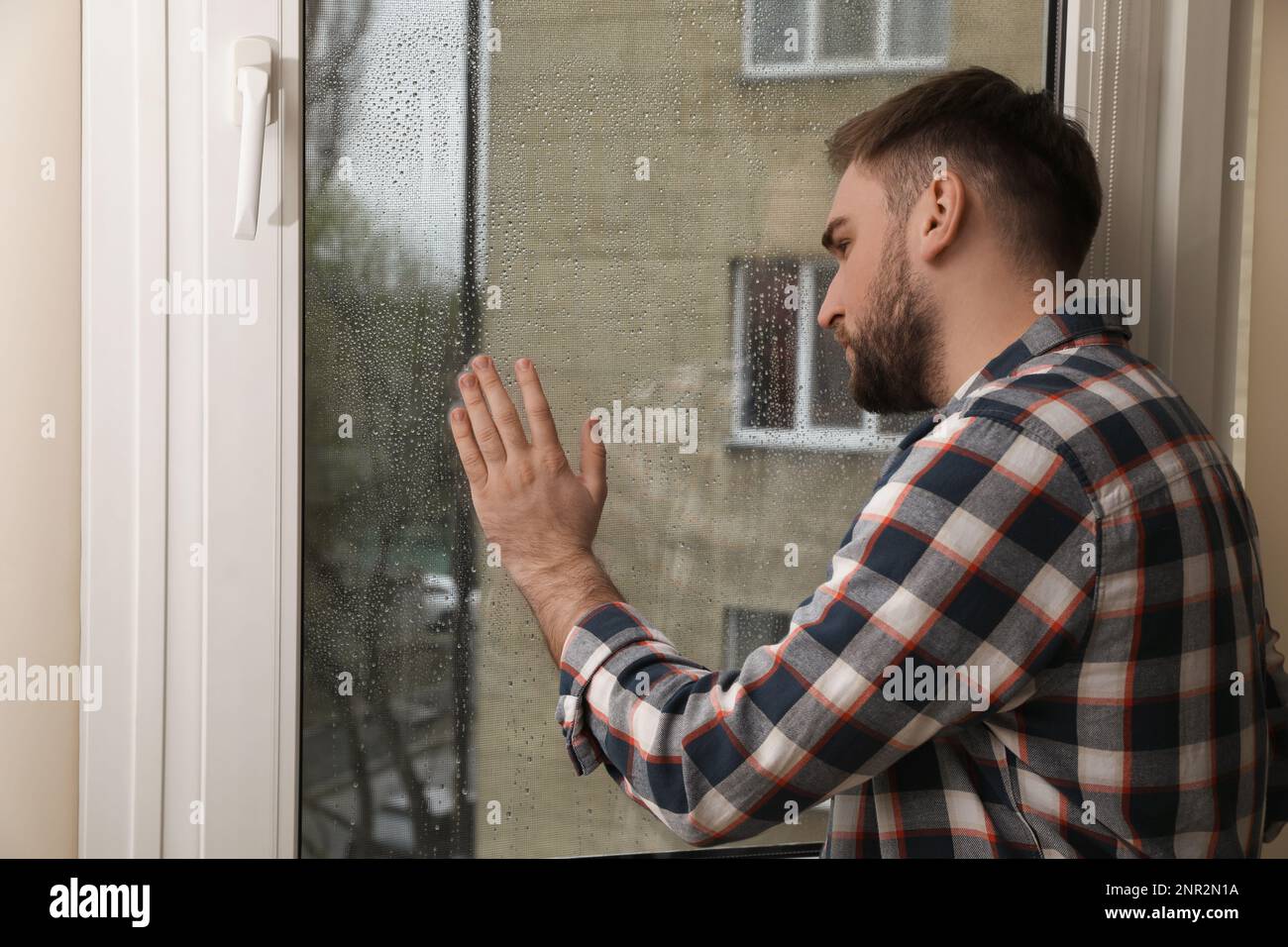 Depressed young man near window at home Stock Photo - Alamy