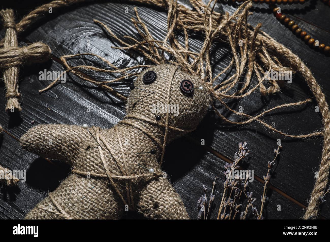 Female voodoo doll with pins surrounded by ceremonial items on black ...