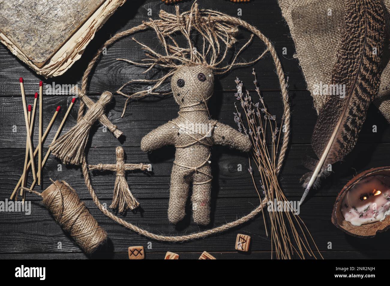 Female voodoo doll with pins surrounded by ceremonial items on black ...