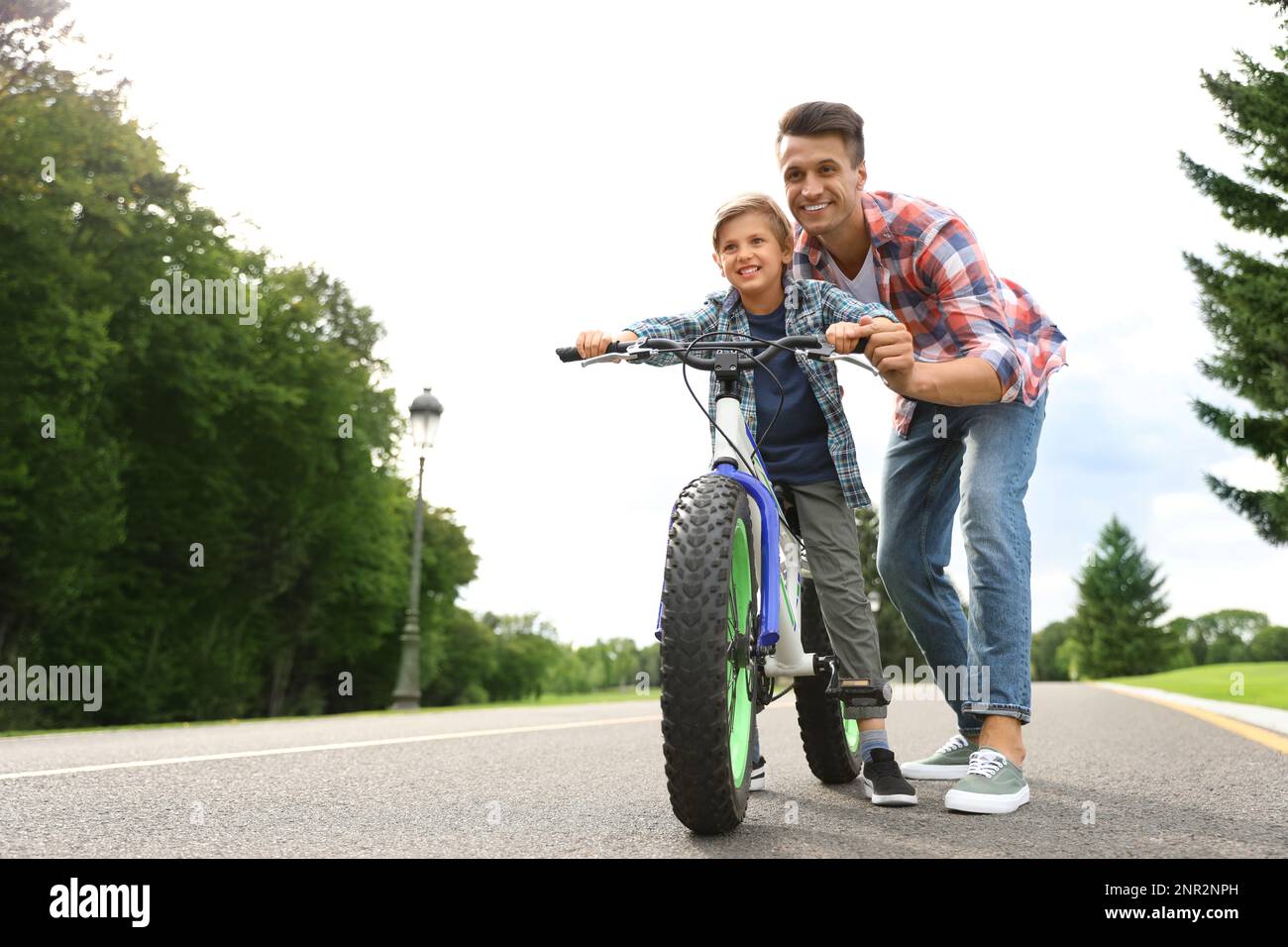 Dad teaching son to ride bicycle outdoors Stock Photo - Alamy