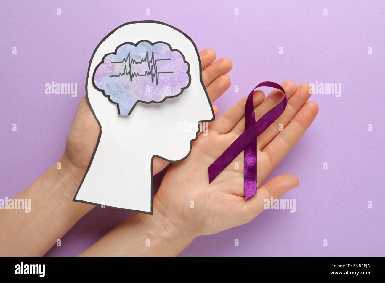 Woman holding human head cutout, brain and purple ribbon at violet ...