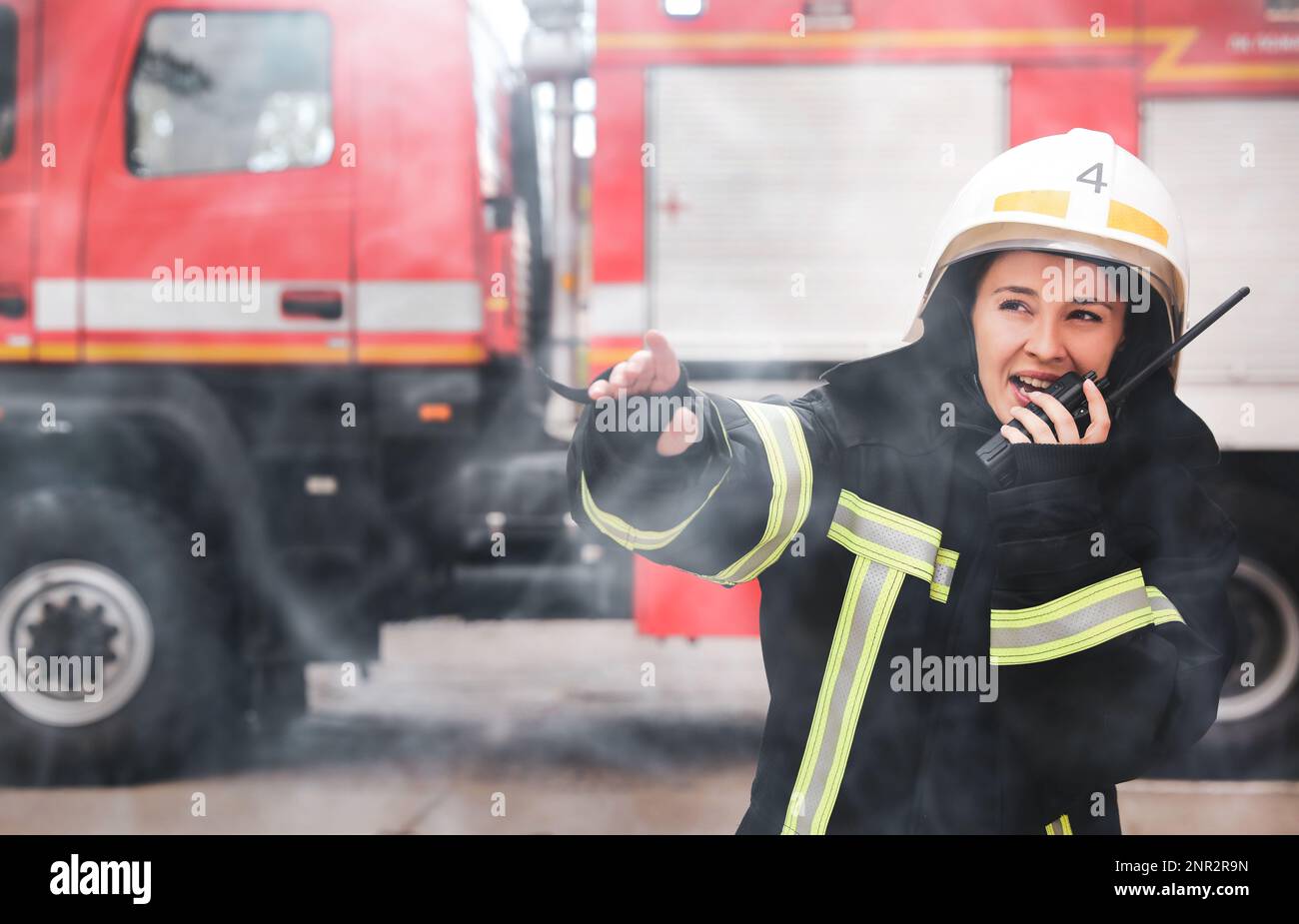Firefighter in uniform using portable radio set near fire truck ...