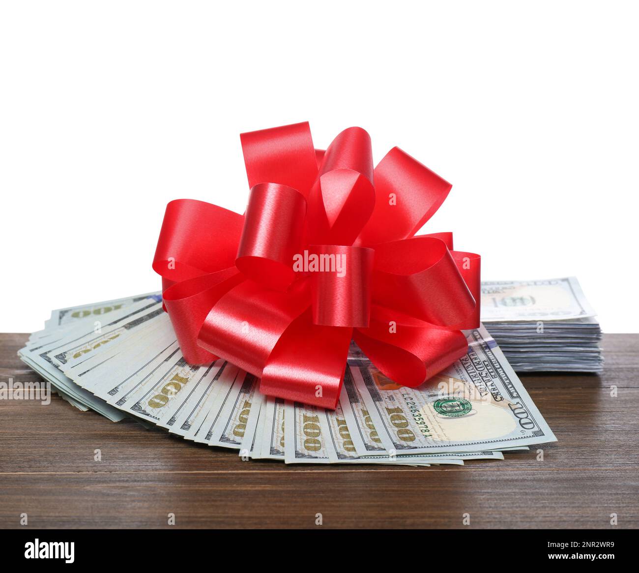 Dollar bills with red bow on wooden table against white background ...