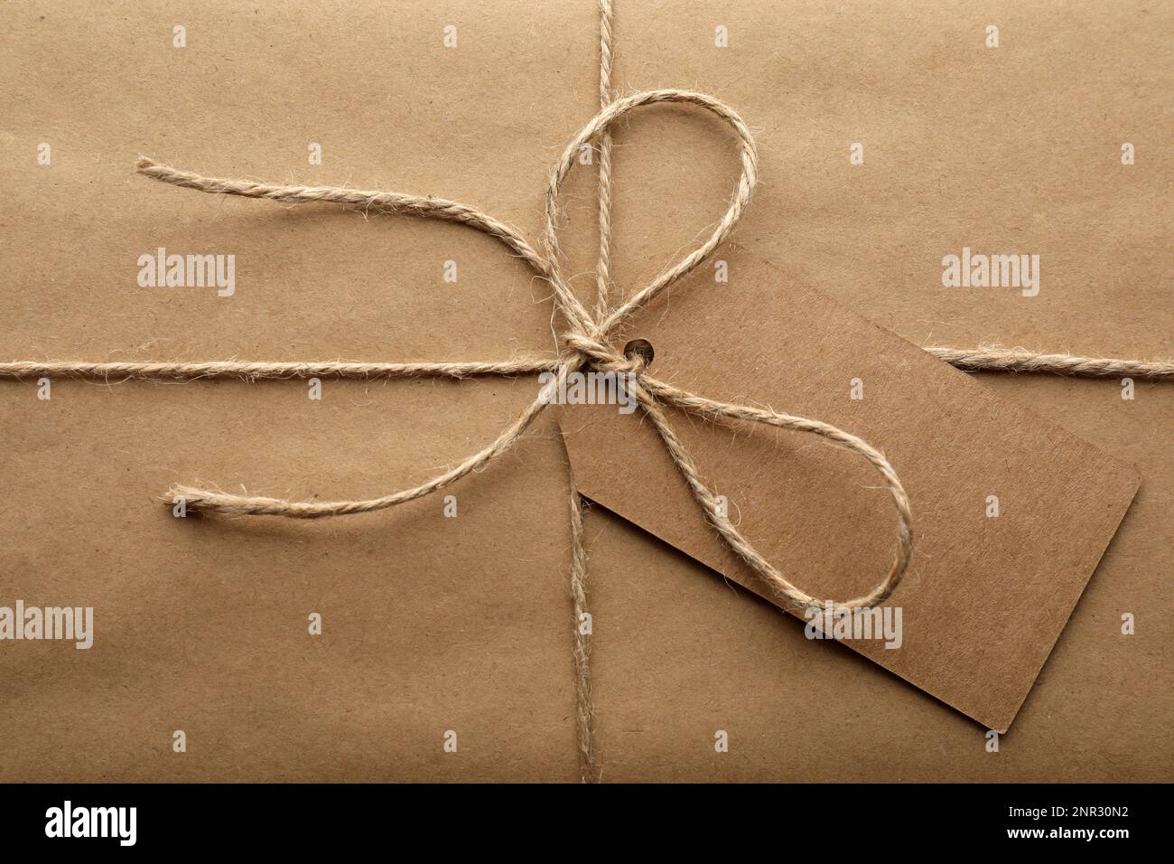 Parcel wrapped in kraft paper with tag as background, closeup Stock ...