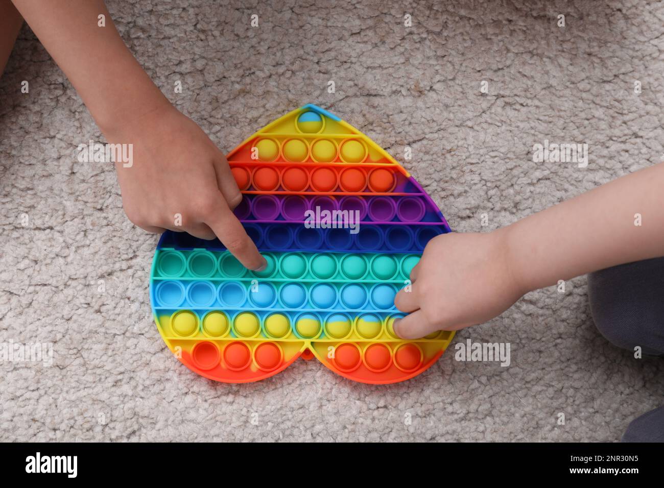 Little children playing with pop it fidget toy on floor, top view Stock ...