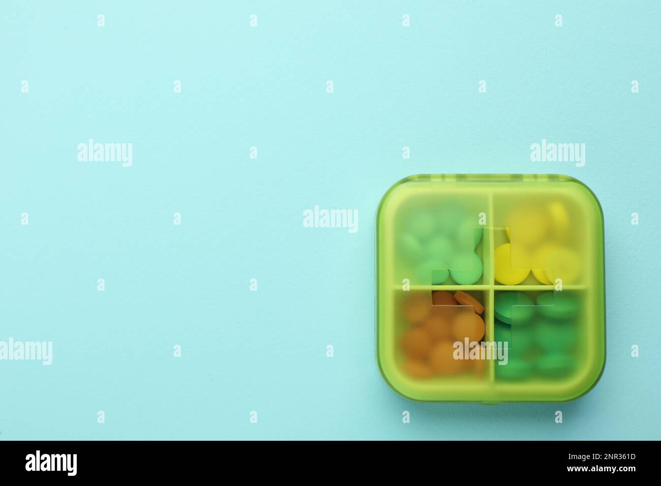Pill box with medicaments on turquoise background, top view. Space for ...