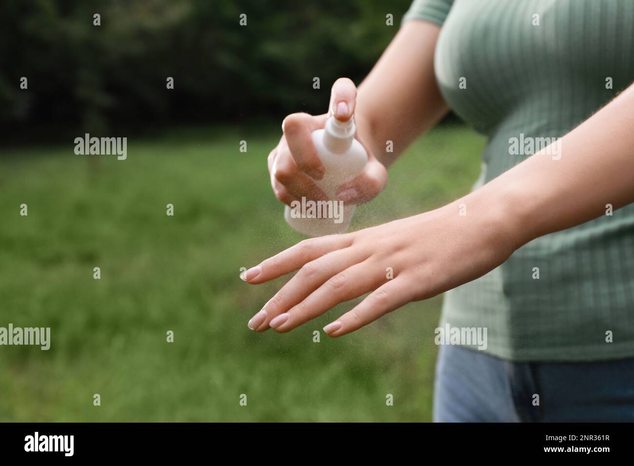Woman applying insect repellent onto hand in park, closeup. Tick bites ...