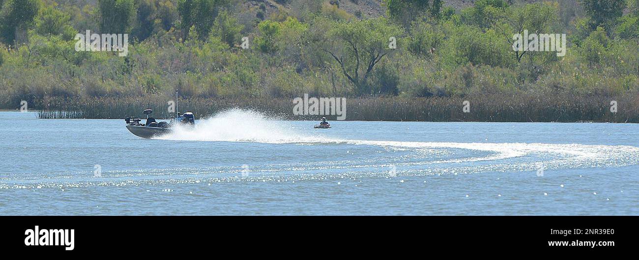 An outboard boat makes a turn on Mittry Lake near where a fisherman is ...