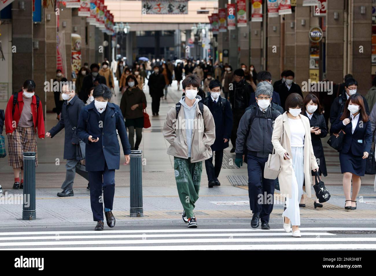 Commuters wearing masks make their way on a street in Sendai, north of ...