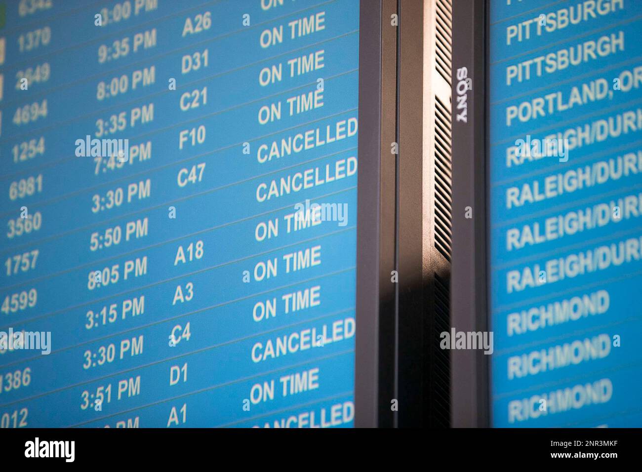 Cancelled flights are displayed on an electronic screen inside the ...