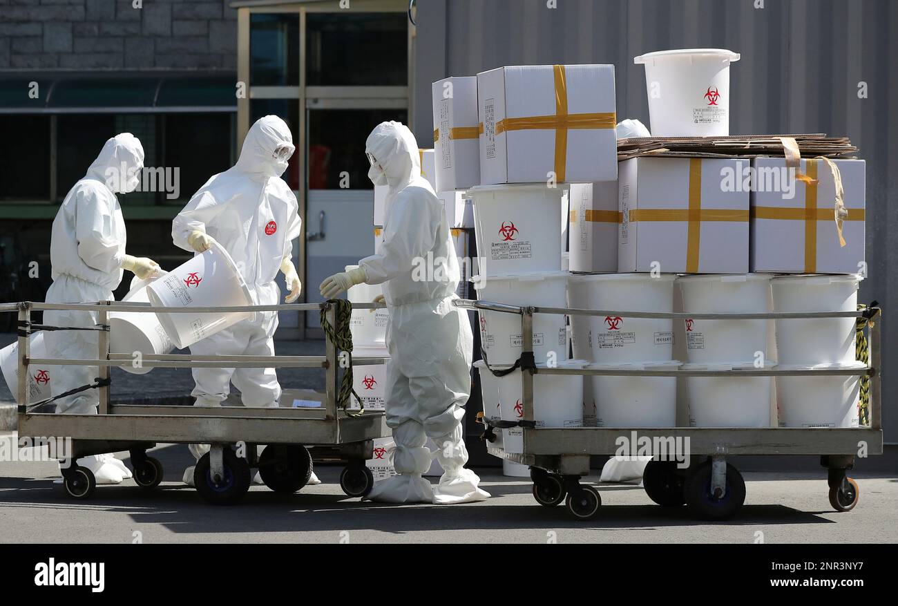 Medical staff members in protective gears stack plastic buckets ...