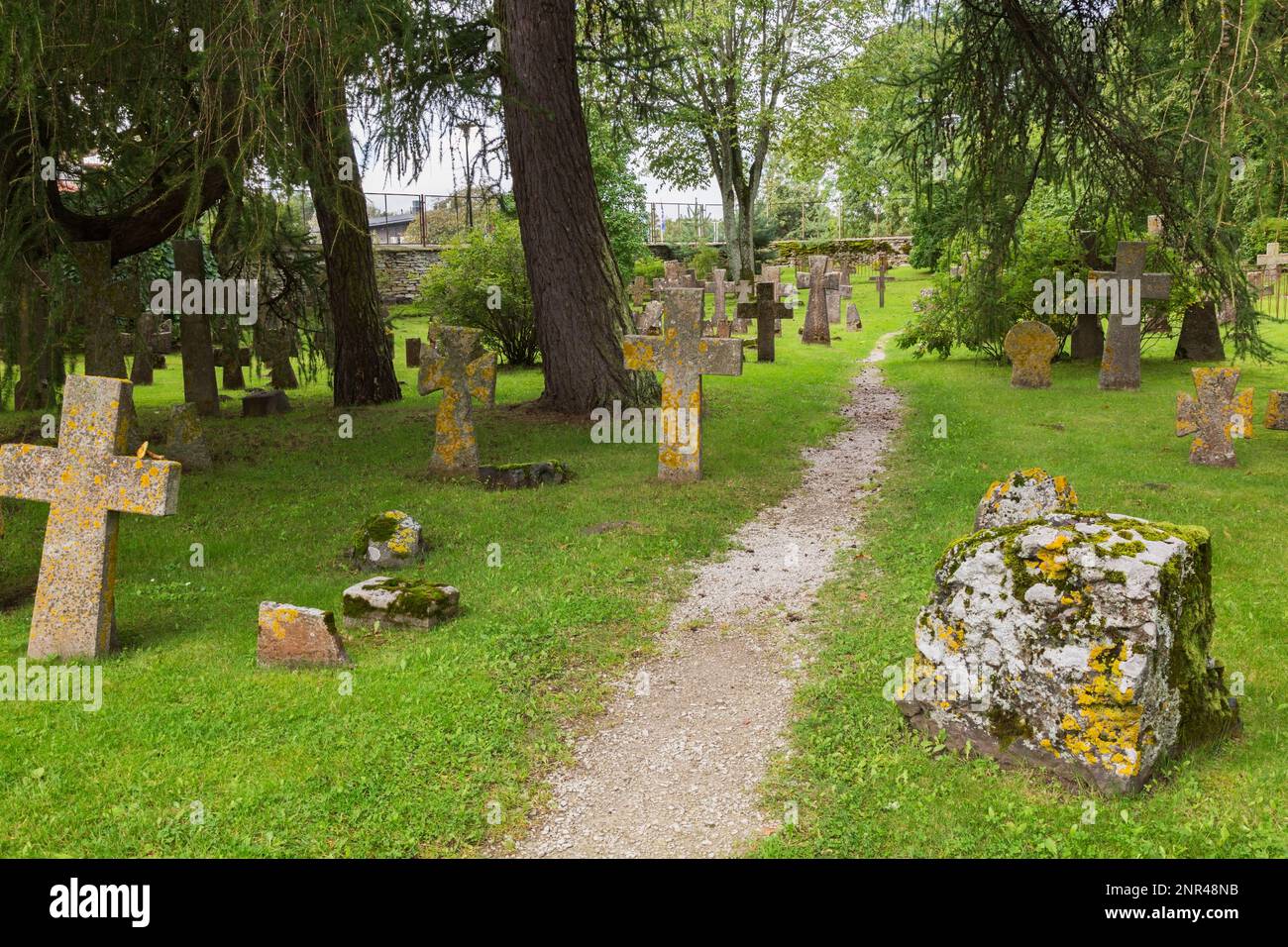 Gravel path through cemetery with old moss and lichen growth on crosses ...