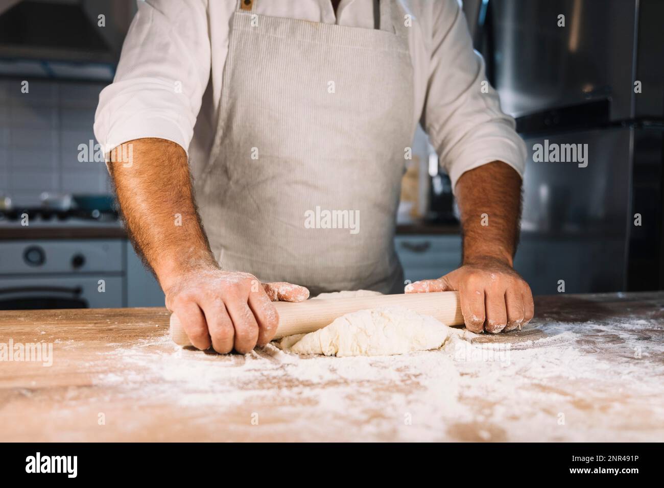Close up male baker s hand flattening dough with rolling pin Stock ...