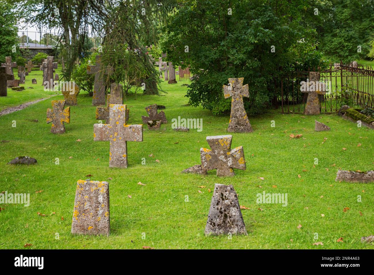 Old moss and lichen covered stone crosses on top of graves in cemetery ...