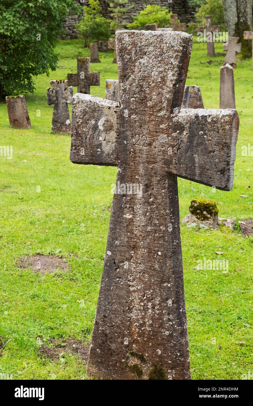Moss and lichen growth covered stone cross on top of grave in cemetery ...