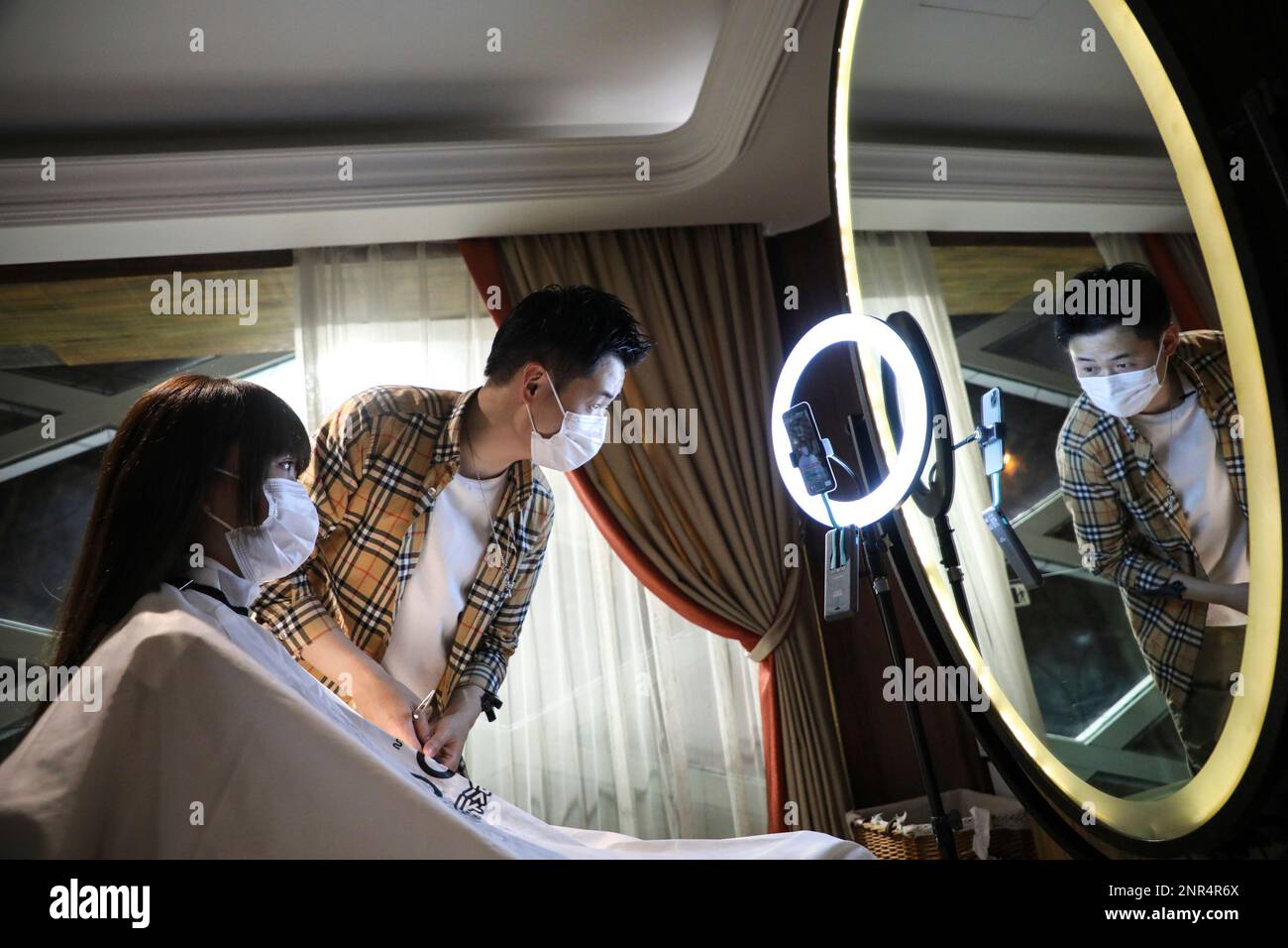 A hairdresser prepares to live stream haircutting in a hair salon in ...