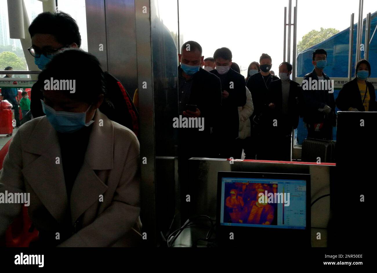 Masked travelers line up to enter a railway station in Yueyang in south ...