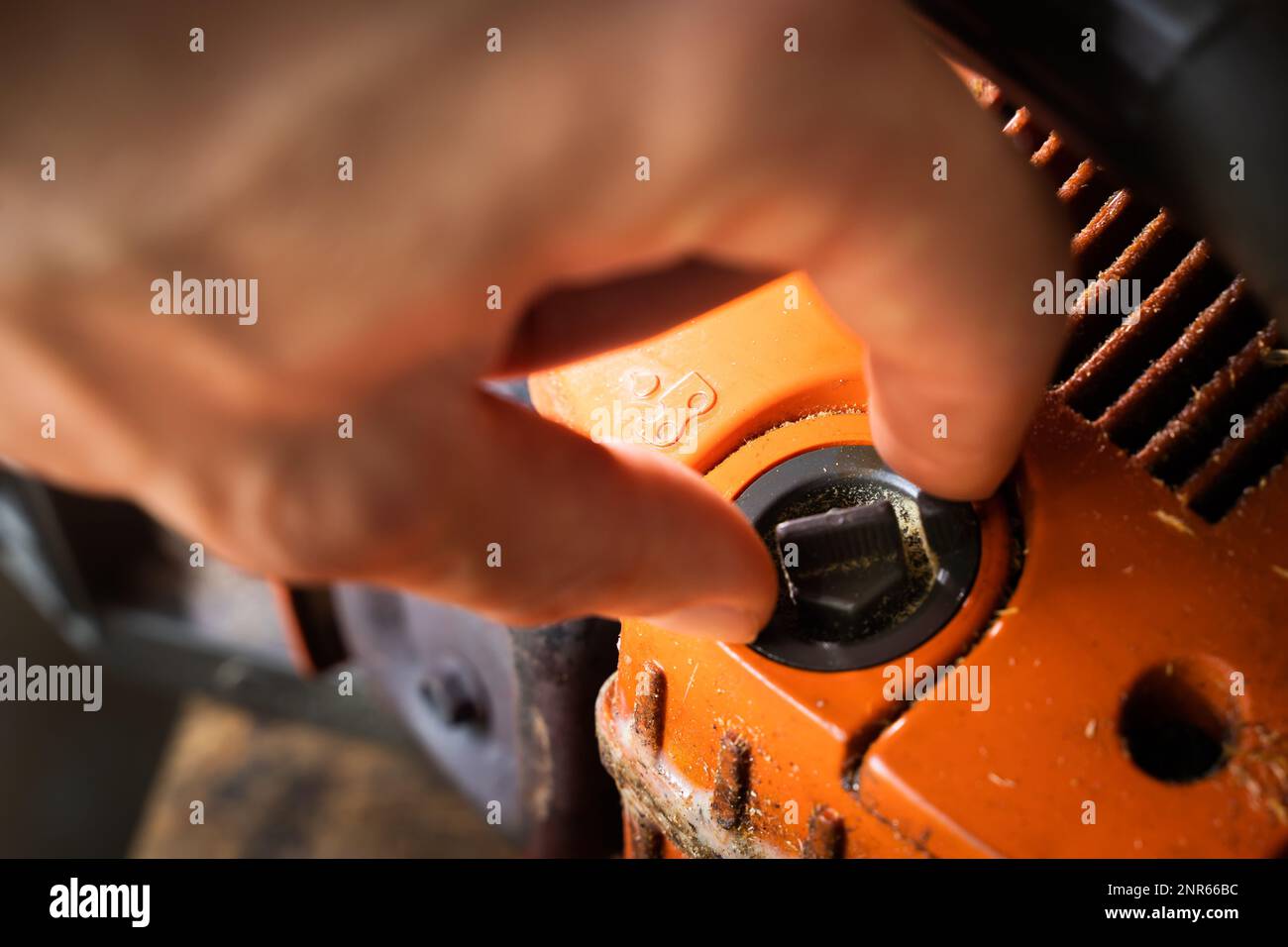 The hand unscrews the oil tank cap for the lubricant mixture in the ...
