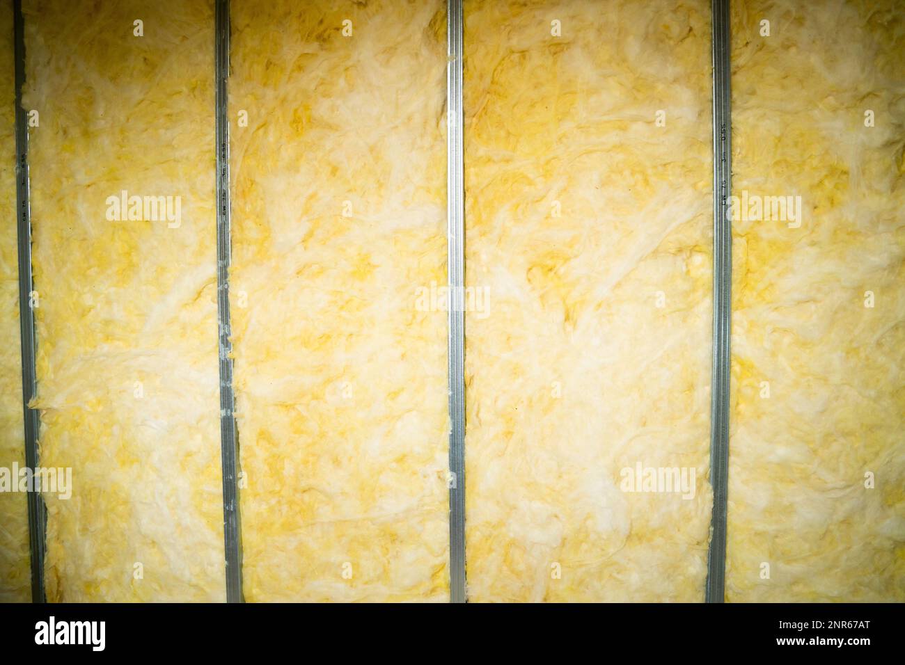 Rolled glass wool is laid between a metal profile in a frame interior ...