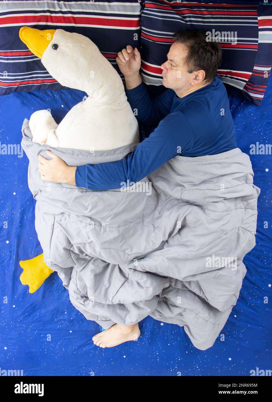 A man sleeps on a bed in an embrace with a large plush toy - stuffed ...