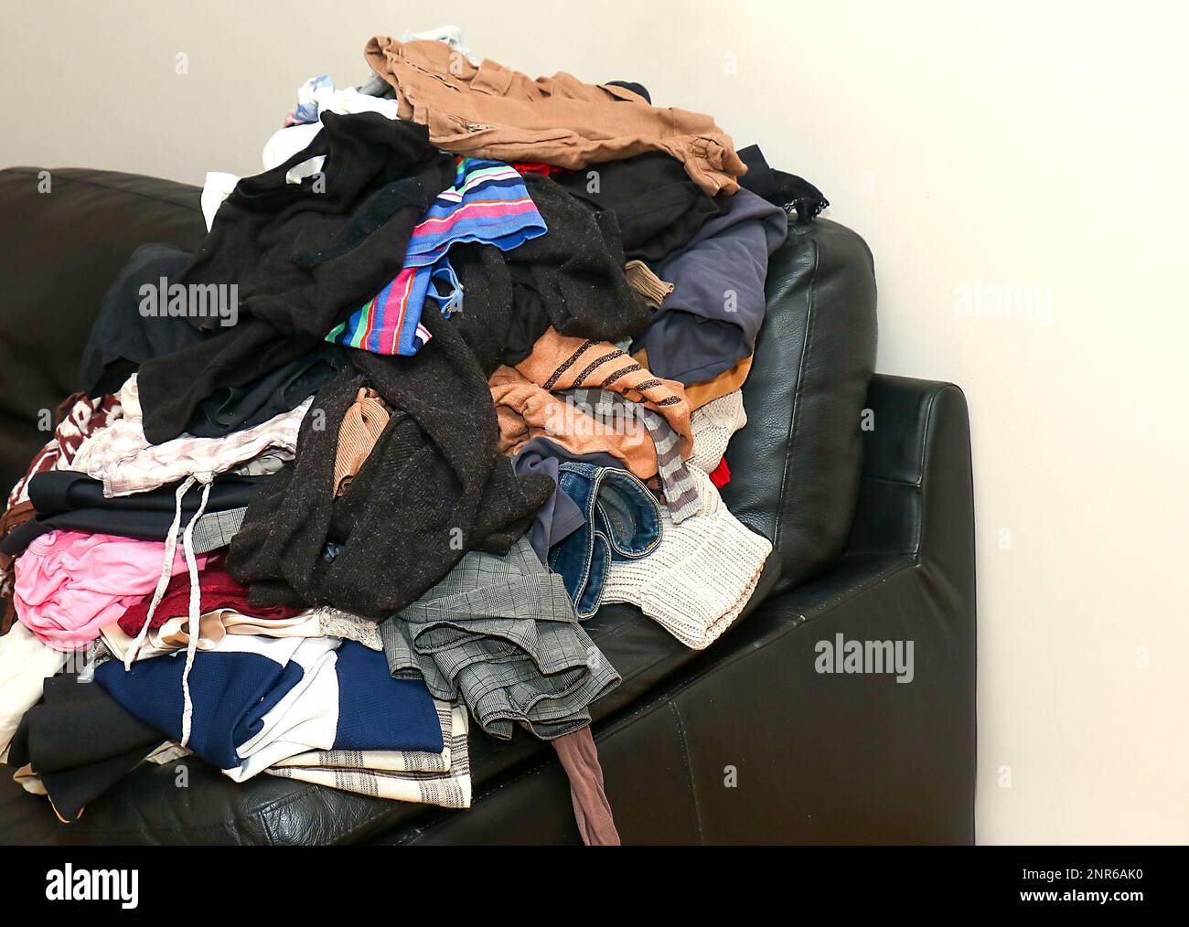 Pile of dirty used worn clothes left on sofa interior Stock Photo - Alamy
