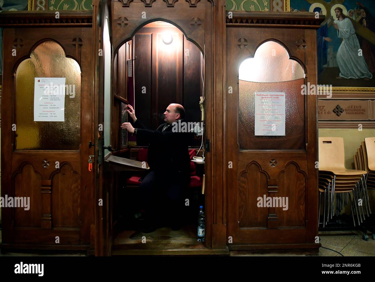 Hungarian priest Laszlo Monostori covers the grid of the confession ...