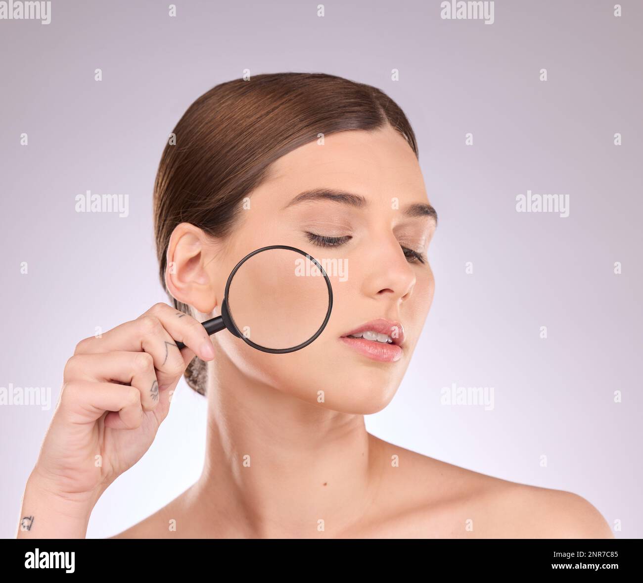 Woman, magnifying glass and face in studio for beauty, cosmetics and ...