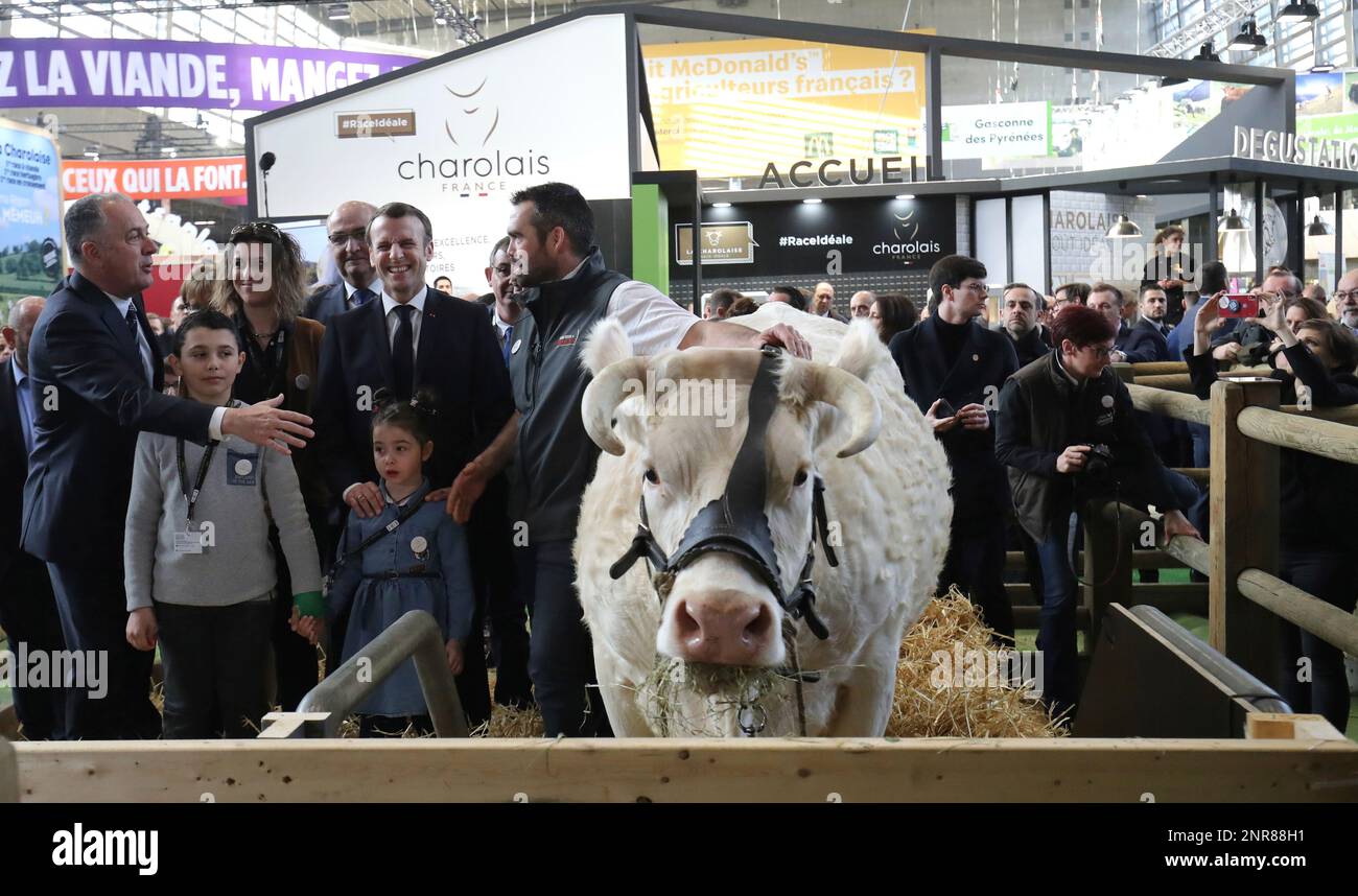 French President Emmanuel Macron poses for a picture near a cow named ...