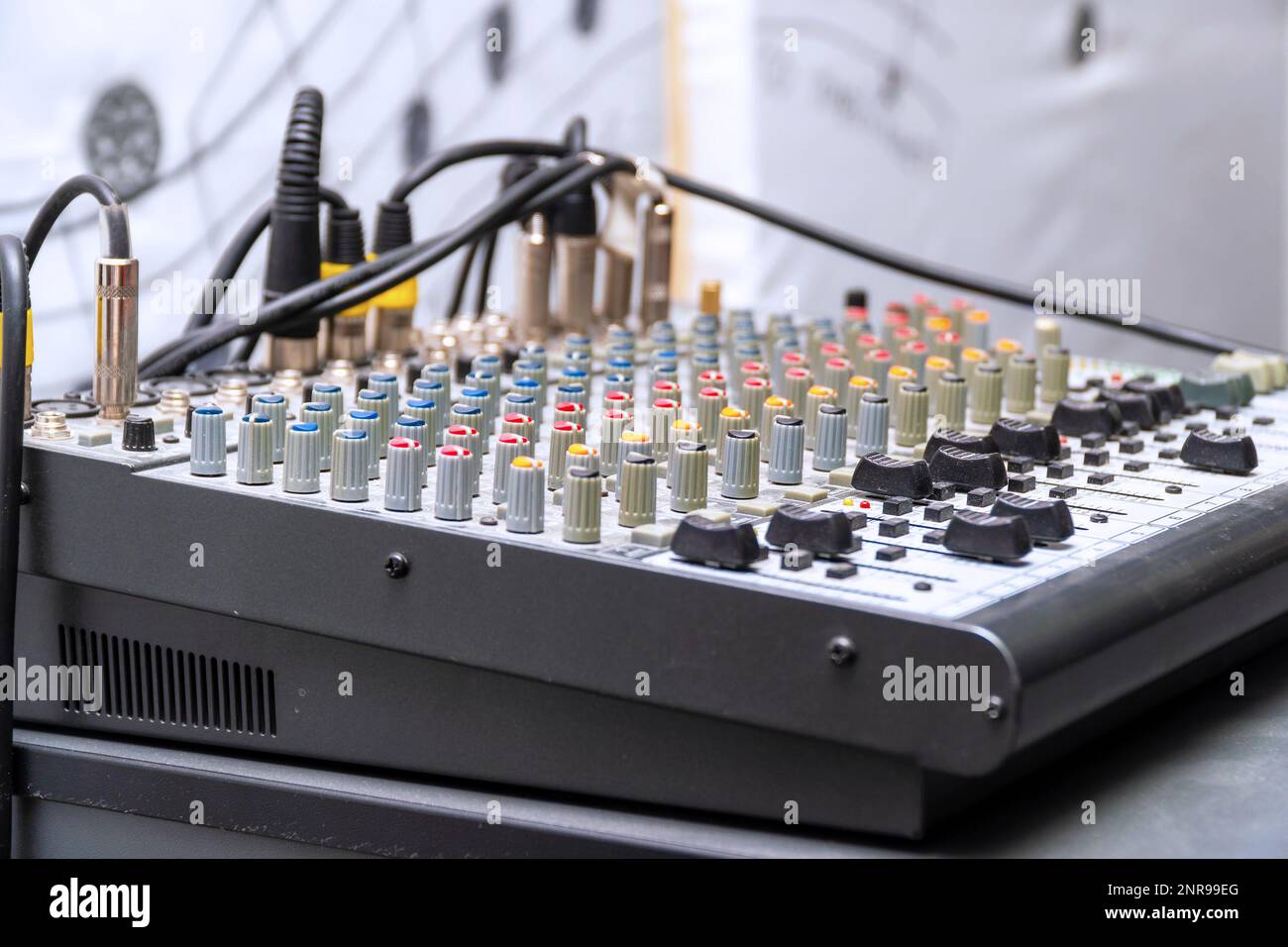A small mixing console with cables with jacks inserted into console ...